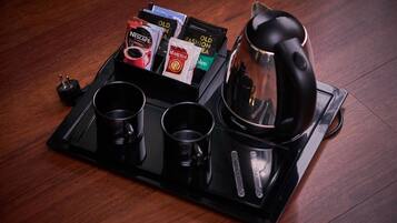 Uma cafeteira, duas chávenas e cápsulas de café numa bandeja.
