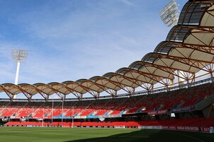 Um estádio com arquibancadas escalonadas e um amplo campo central.