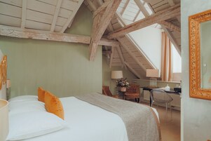 Quarto com cama, escrivaninha, cadeira, abajur e um espelho grande.