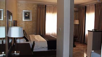 Quarto de hotel com cama, escrivaninha, cadeira, luminária e espelho.