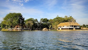 Uma propriedade à beira do lago com construções de telhado de palha e um edifício grande com varandas.
