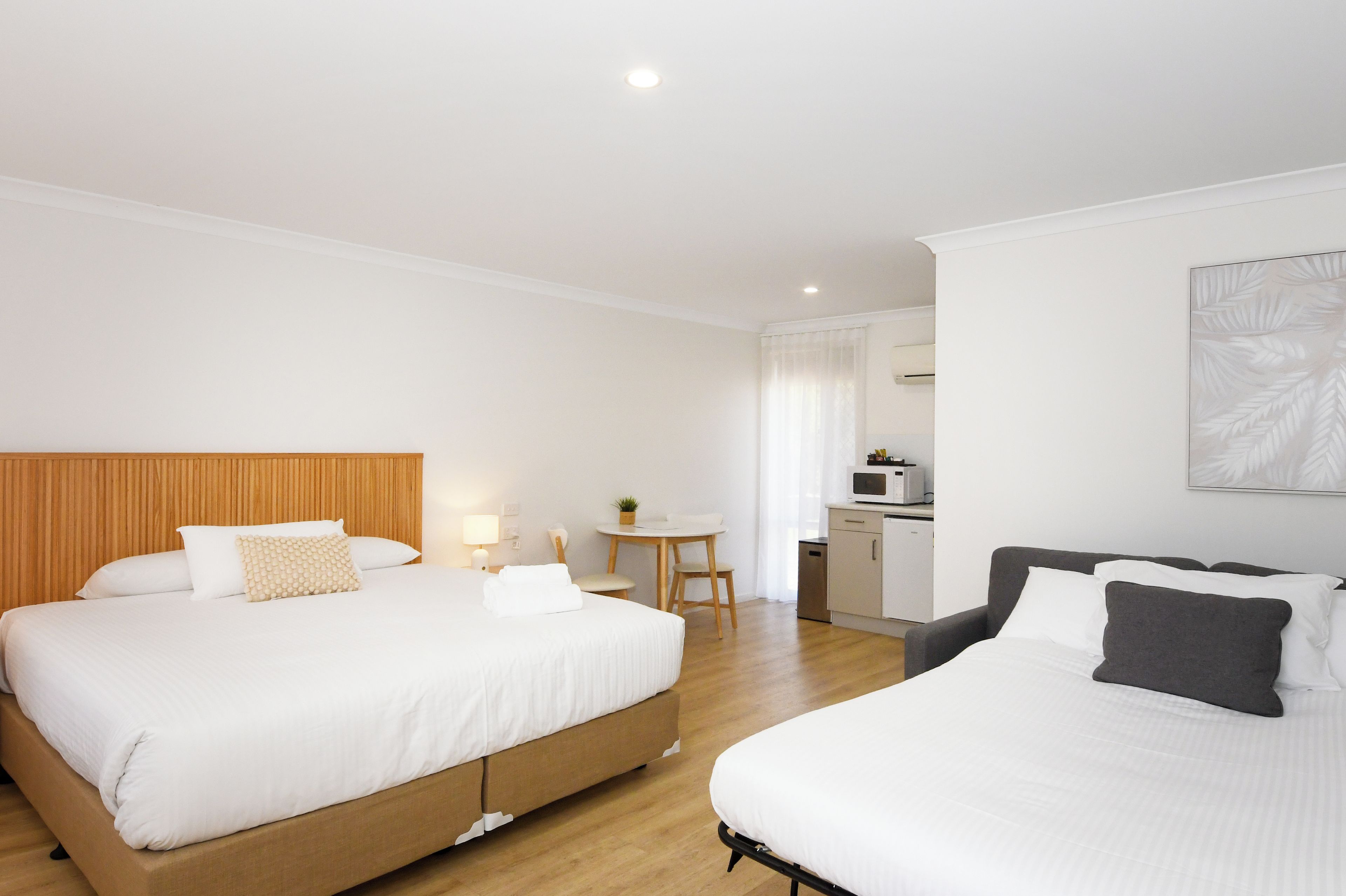 Quarto de hotel com duas camas, uma kitchenette e uma área de refeições.