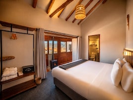 Quarto de hotel com cama grande, armário de madeira, lareira e vista para o exterior.