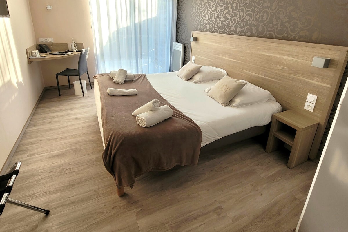 Quarto de hotel com uma cama grande, uma escrivaninha e uma cadeira.
