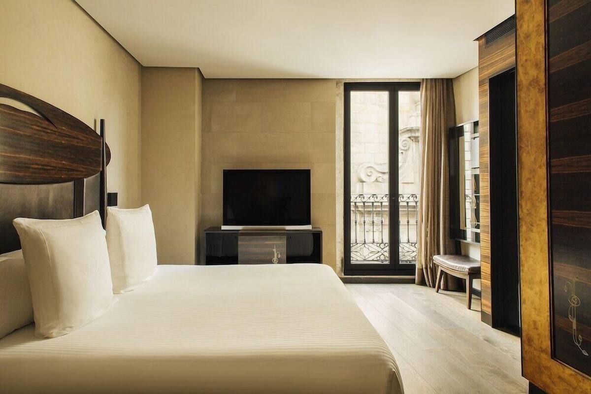 Quarto de hotel com cama, televisão, varanda e vista, e um guarda-roupa.