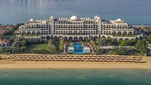 Um grande resort com vários edifícios, uma piscina central e área de praia.