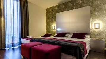 Quarto de hotel com uma cama grande, duas mesas de cabeceira, uma escrivaninha e uma janela com cortinas.