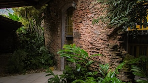 Um edifício de pedra com uma janela e vegetação exuberante.