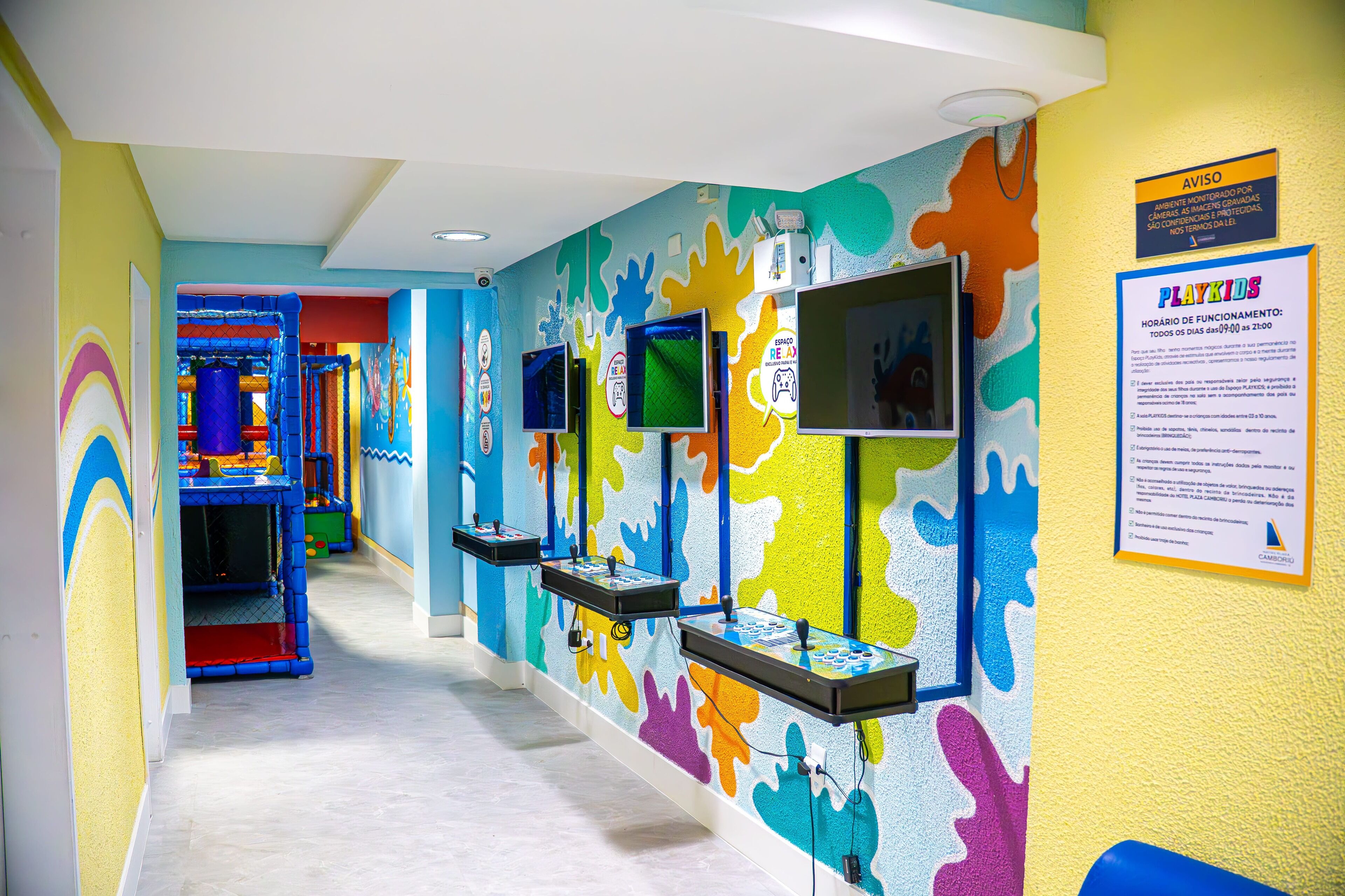Uma área de recreação colorida com um mural, estruturas de jogos e uma placa PlayKids.