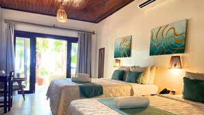 Quarto de hotel com duas camas, área de refeições e vista para o exterior.