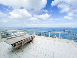 Varanda com um banco de madeira, com vista para o mar e para a marina.