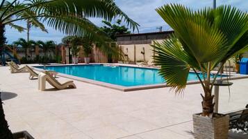 Piscina com espreguiçadeiras e palmeiras.