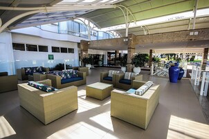 Amplo espaço interno com mobiliário de vime e teto de vidro, oferecendo vista para o exterior.