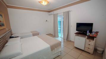 Quarto de hotel com cama, televisão, minibar e vista para o exterior.