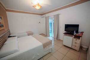 Quarto de hotel com cama, televisão, minibar e vista para o exterior.