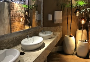 Casa de banho com duas pias, um espelho e plantas decorativas.