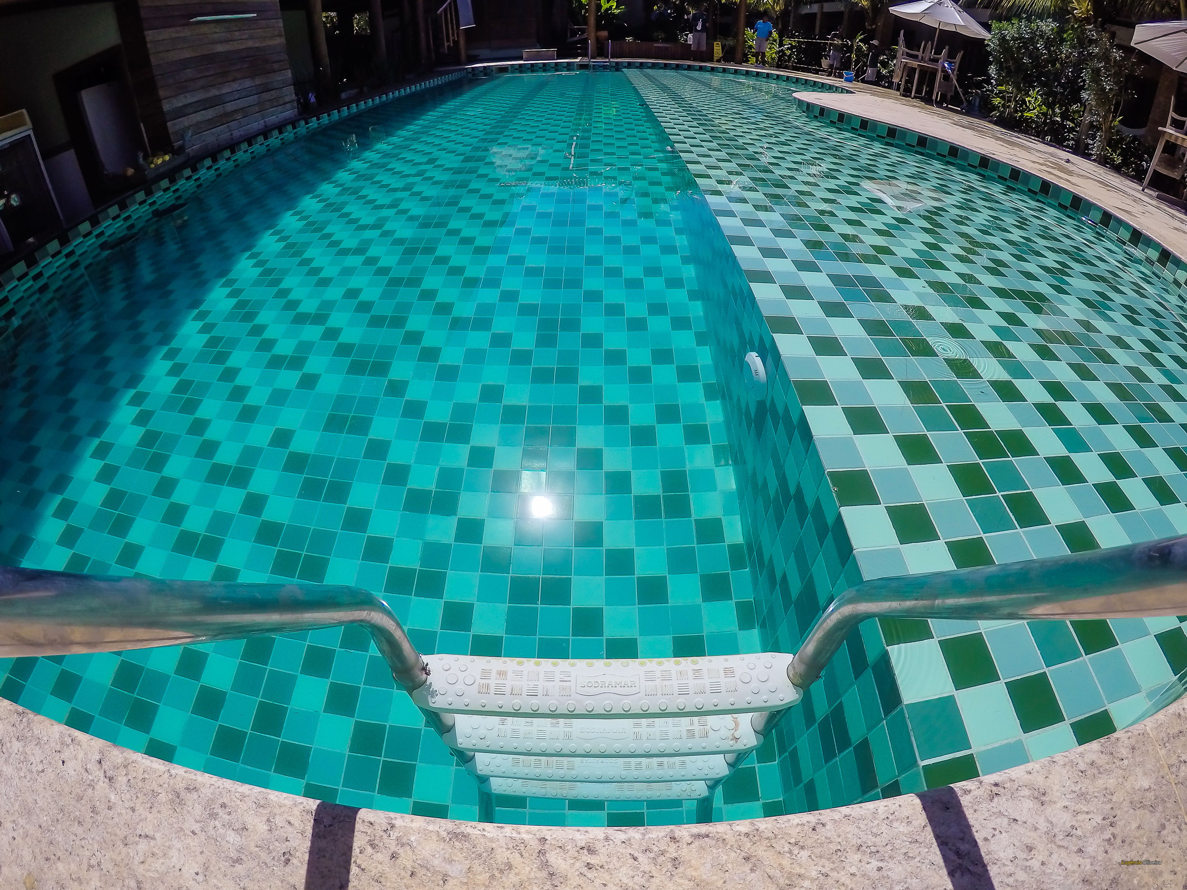 Uma piscina com padrão de azulejos xadrez e um tobo água integrado.