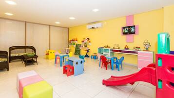 Uma sala de brinquedos infantil, vibrante, com diversos brinquedos e mobiliário.