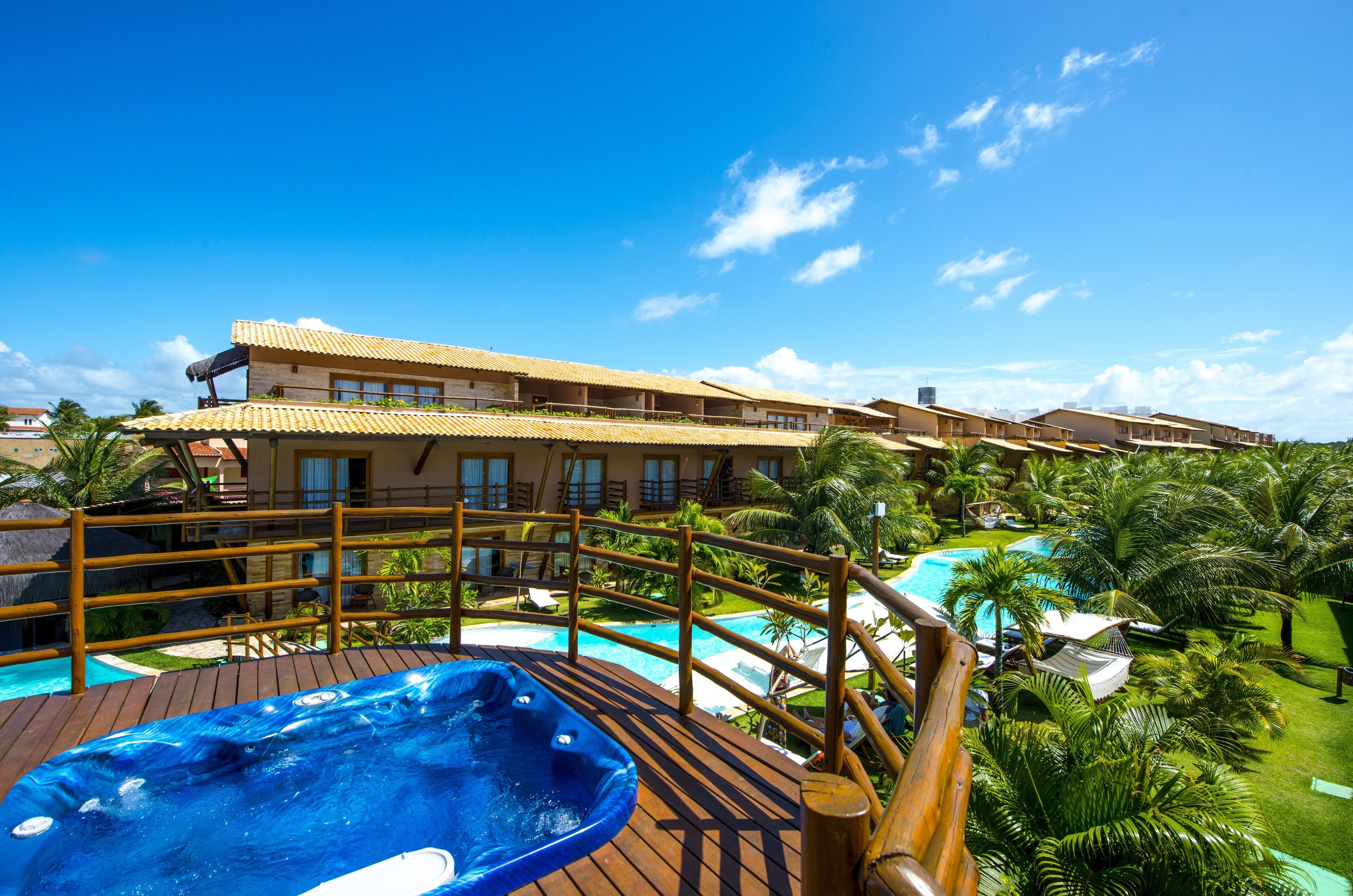 Resort com piscina, banheira de hidromassagem e palmeiras.