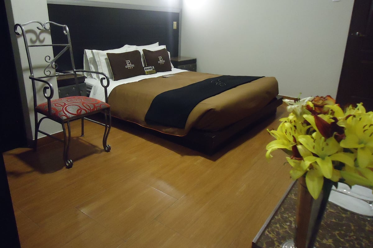 Quarto de hotel com cama, uma cadeira e um vaso de flores.