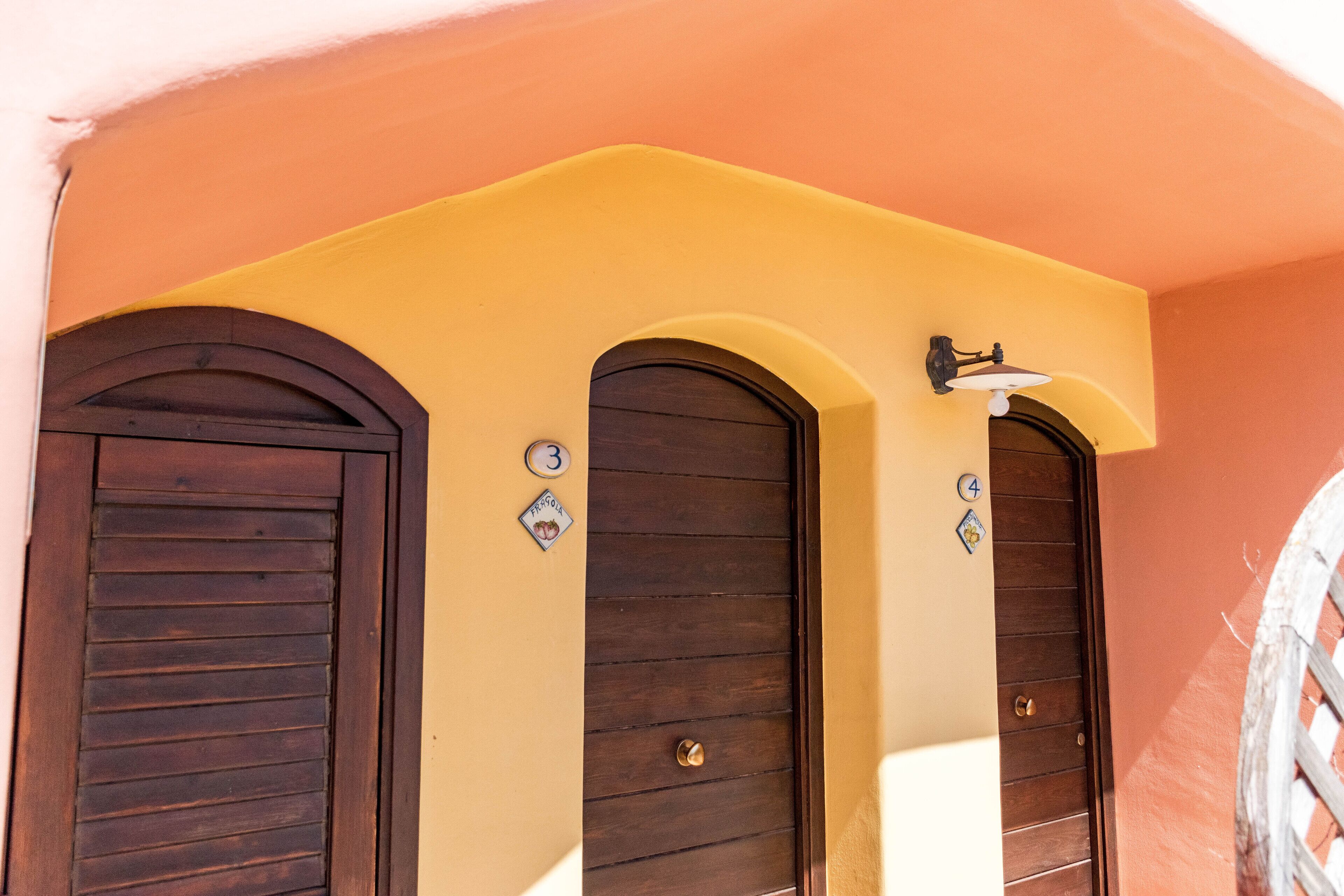 Um edifício com três portas de madeira, cada uma com uma placa de número acima.