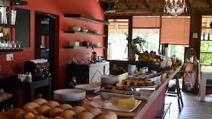Um buffet de café da manhã com diversos alimentos, uma área de bar e um lustre pendurado.