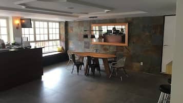 Cozinha moderna com área de jantar, painel de parede em pedra e uma grande janela que traz luz natural.