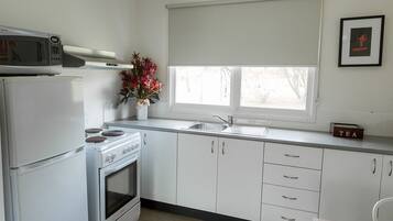 Cozinha moderna com armários brancos, micro-ondas, forno e pia.