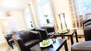 Uma sala de estar moderna com sofás de couro, uma mesa de centro e uma mesa de jantar com uma travessa de frutas.