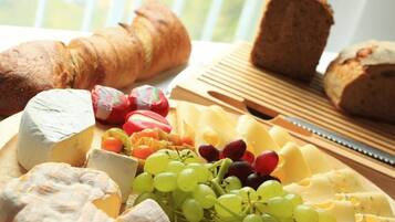 Tábua de queijos com diversos tipos de queijo, uvas e pão sobre uma tábua de madeira.