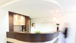 Bancada de recepção com design curvo, um recepcionista e uma parede com uma mensagem de boas-vindas.
