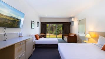 Quarto de hotel com duas camas, uma escrivaninha, uma cadeira, televisão e vista para o exterior.