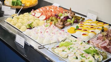 Buffet com diversas opções de comida, incluindo saladas, frutas e carnes.