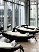 Uma área de spa moderna com espreguiçadeiras de vime, janelas amplas e vista para a cidade.