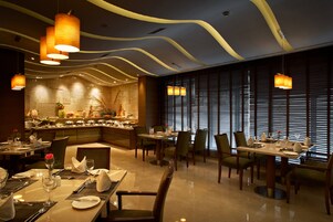 Um restaurante com interior moderno, apresentando um bar, mesas e cadeiras.