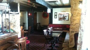 Um espaço de bar aconchegante com móveis de madeira, um alvo de dardos e uma mesa de bilhar.