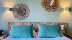 Uma cama com duas almofadas verde-água e cabeceira de madeira.