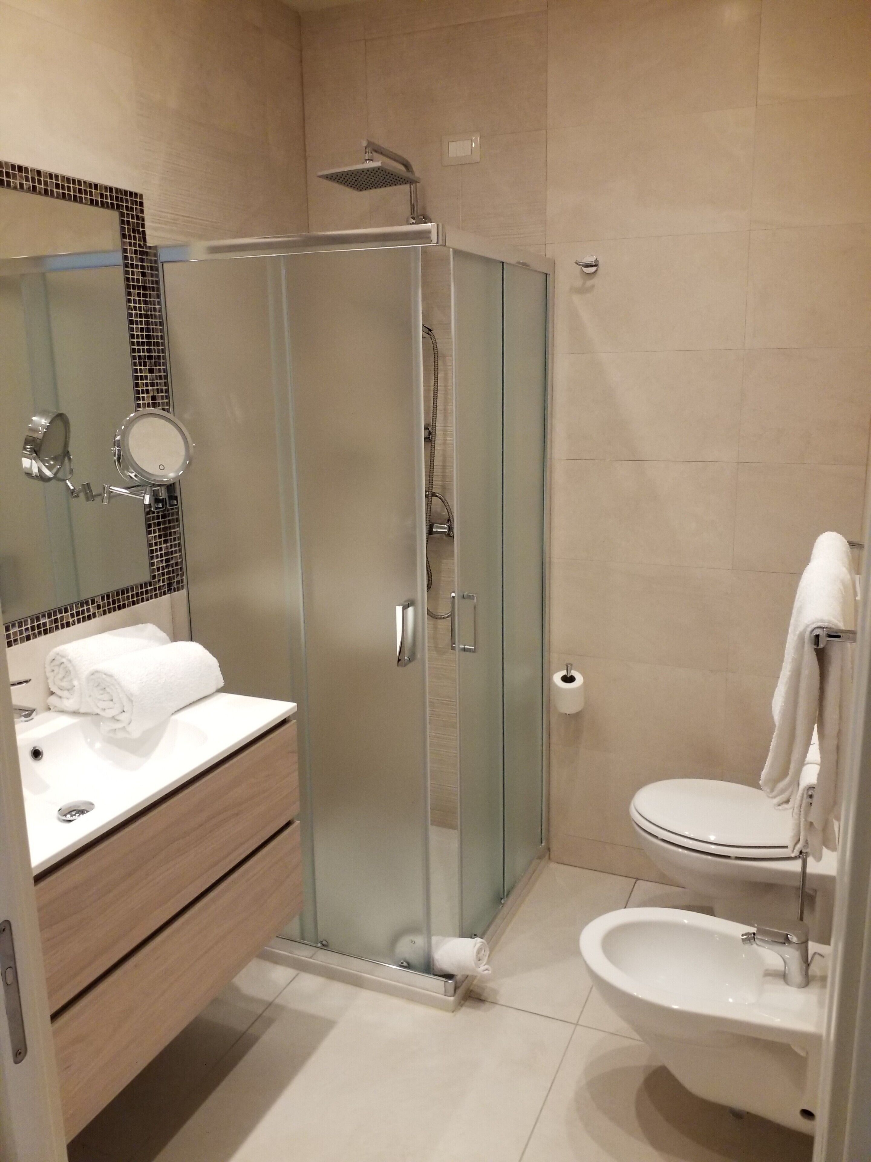 Uma casa de banho moderna com chuveiro envidraçado, lavatório com espelho e sanita.