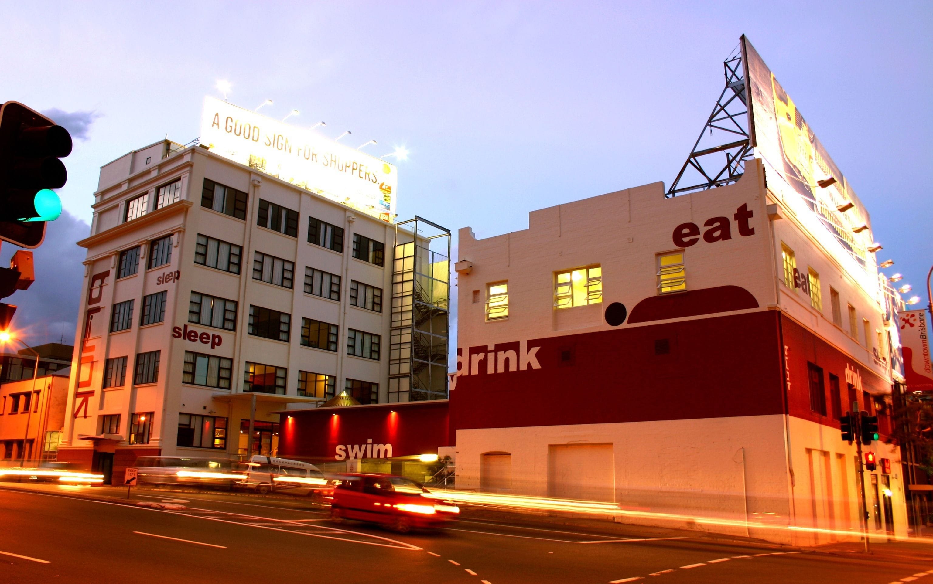 Um edifício com uma placa que diz "A GOOD SIGN FOR SHOPPERS" e outra placa com a inscrição "eat drink".