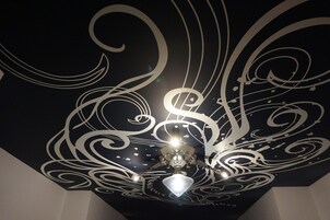 Teto com espirais brancas detalhadas e um lustre central.