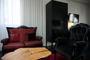 Um quarto com um sofá de couro vermelho, uma poltrona preta e uma mesa de centro de madeira.