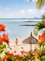 Na praia, areia branca, espreguiçadeiras, guarda-sóis 