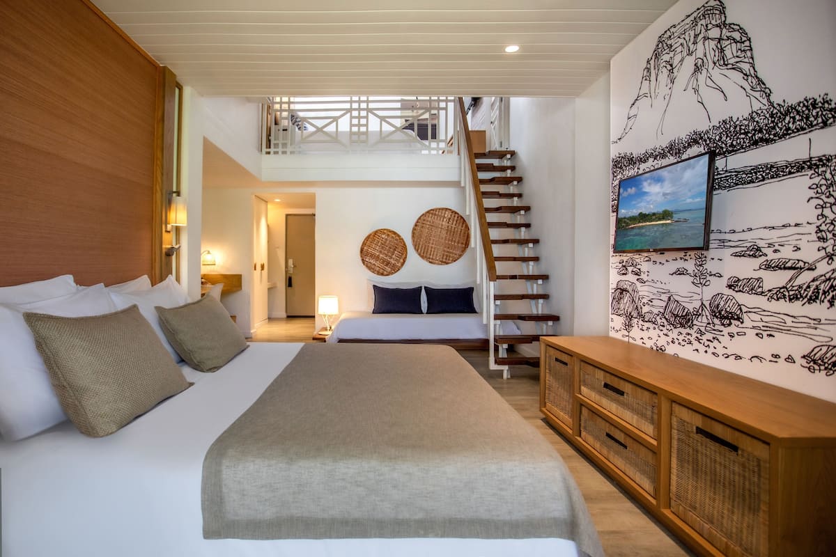 Quarto com cama grande, cabeceira de madeira, escada e parede com pintura de paisagem.