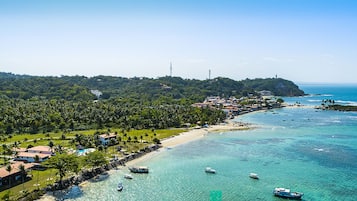 Na praia, areia branca, espreguiçadeiras, guarda-sóis