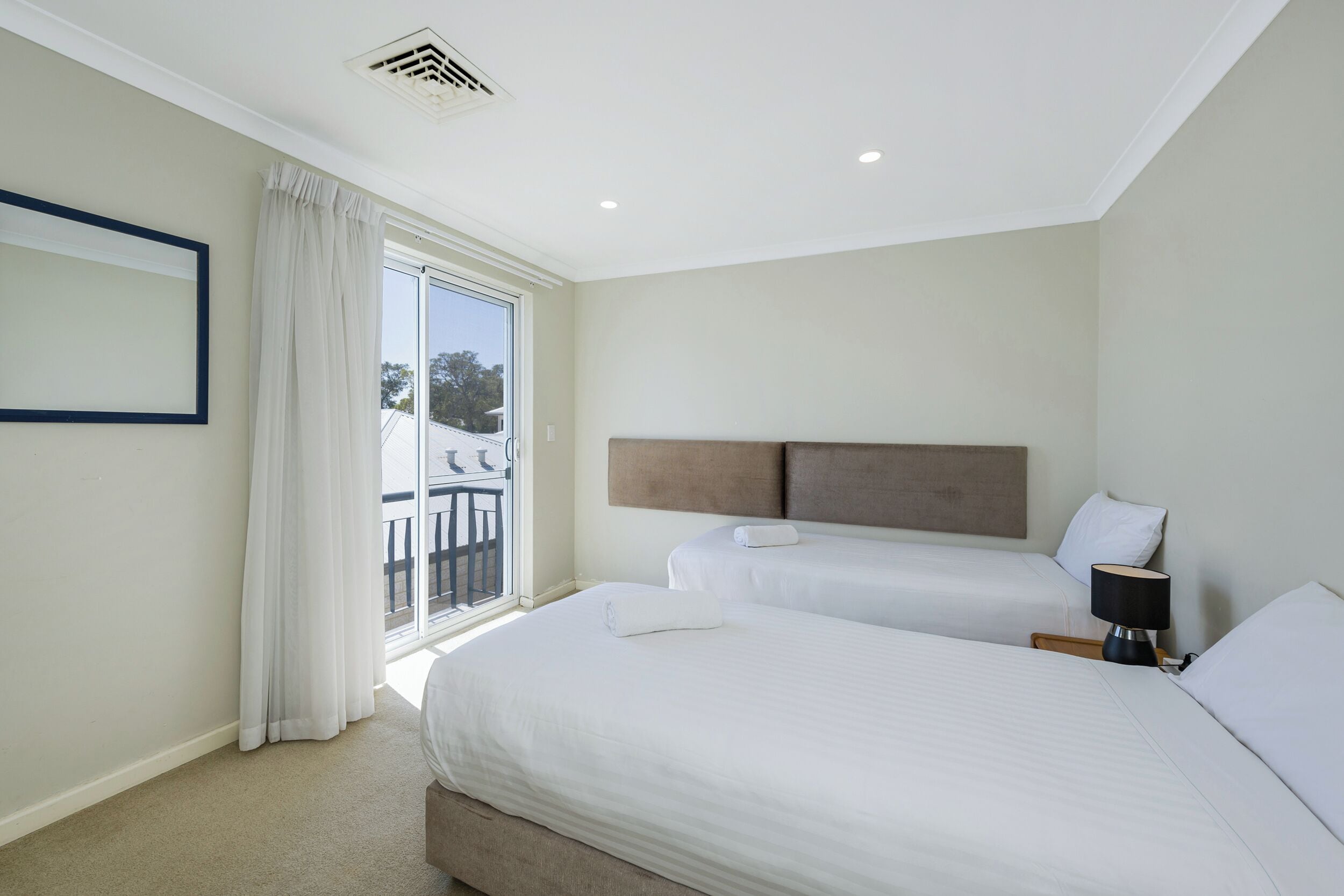 Quarto de hotel com duas camas, uma janela grande e vista para o exterior.