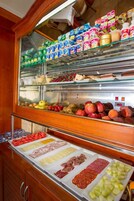Buffet com diversas opções de comida, incluindo frutas, queijos e carnes.