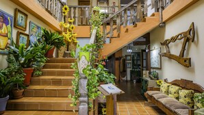 Uma escadaria com plantas em vasos, um banco de madeira e uma área de recepção.