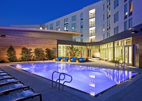 Um hotel moderno com piscina, área de estar externa e fachada bem iluminada.