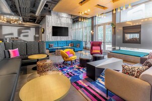 Espaço lounge moderno com sofá azul, poltrona amarela e diversas opções de assentos.