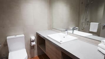 Uma casa de banho moderna com sanita, lavatório e chuveiro.